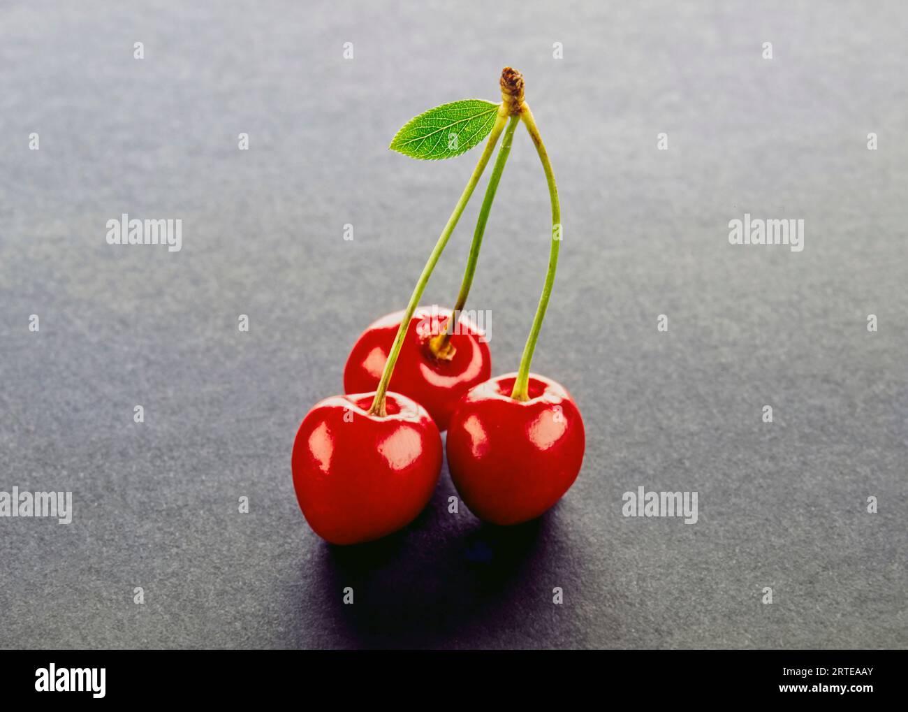 Three cherries with stem and leaf Stock Photo - Alamy
