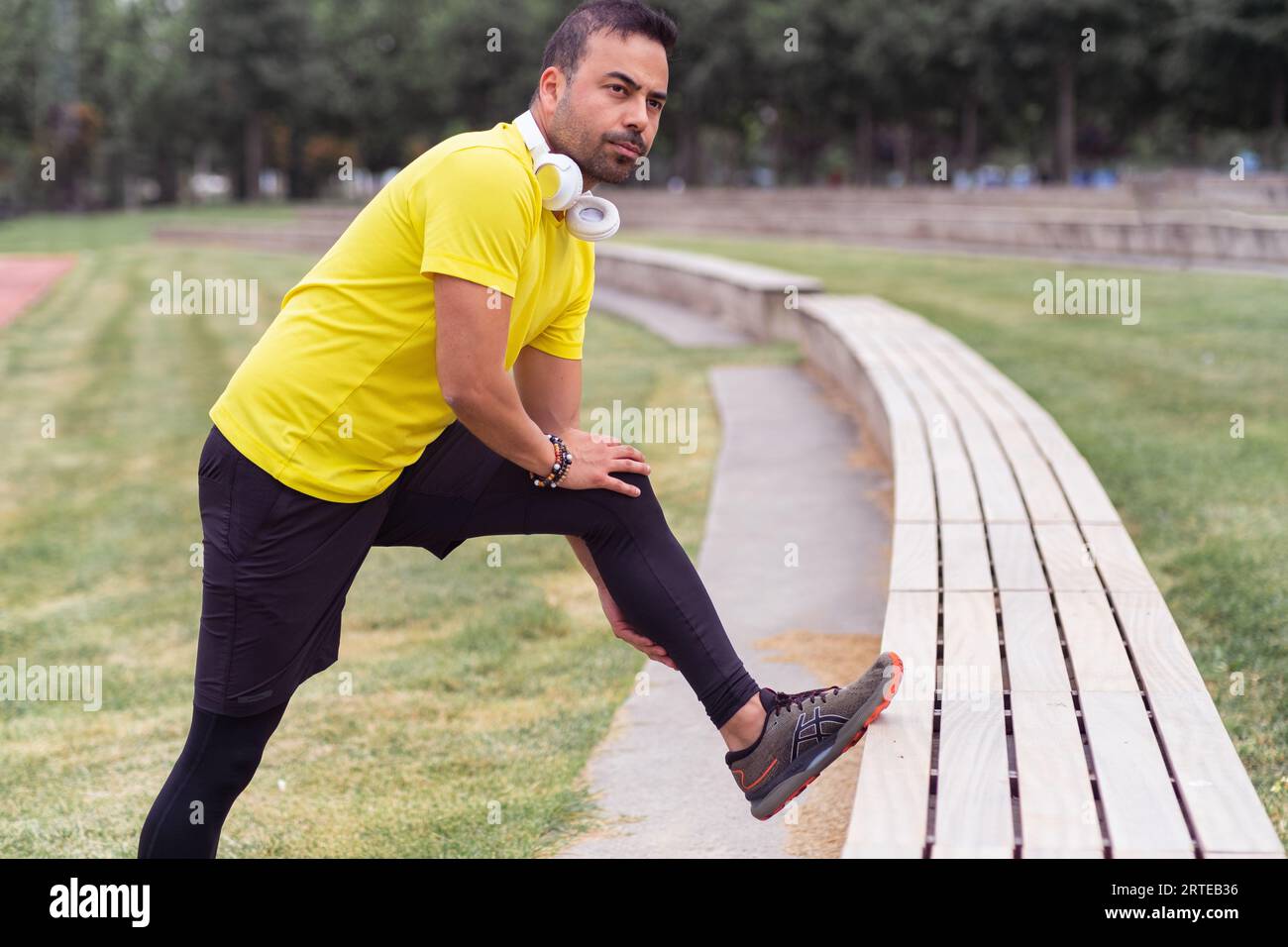 Demonstrating flexibility in urban park, man in yellow t-shirt do ...