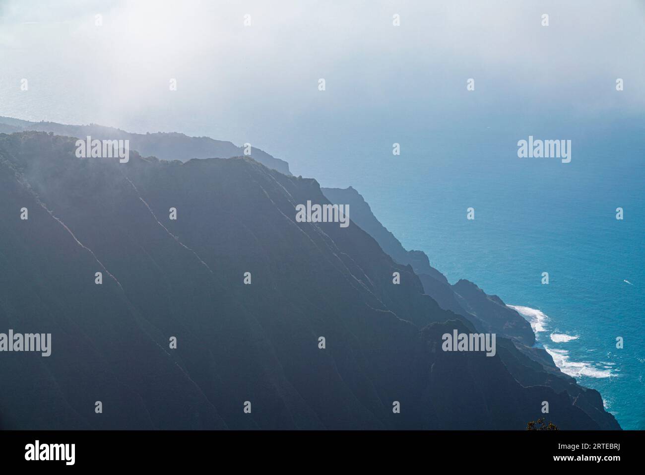 Hazy view of the steep, silhouetted mountain cliffs of the Napali Coast ...