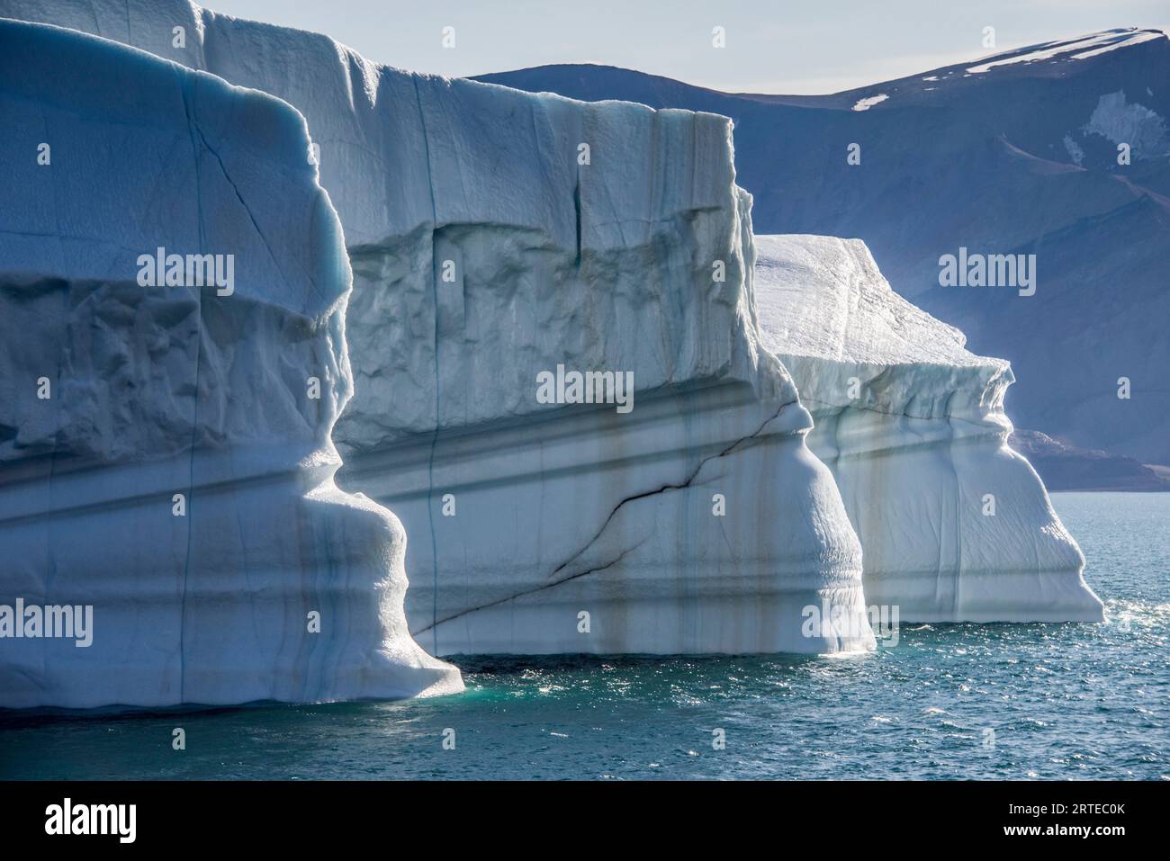Close-up of a large iceberg with silty streaks floating in the icy blue ...