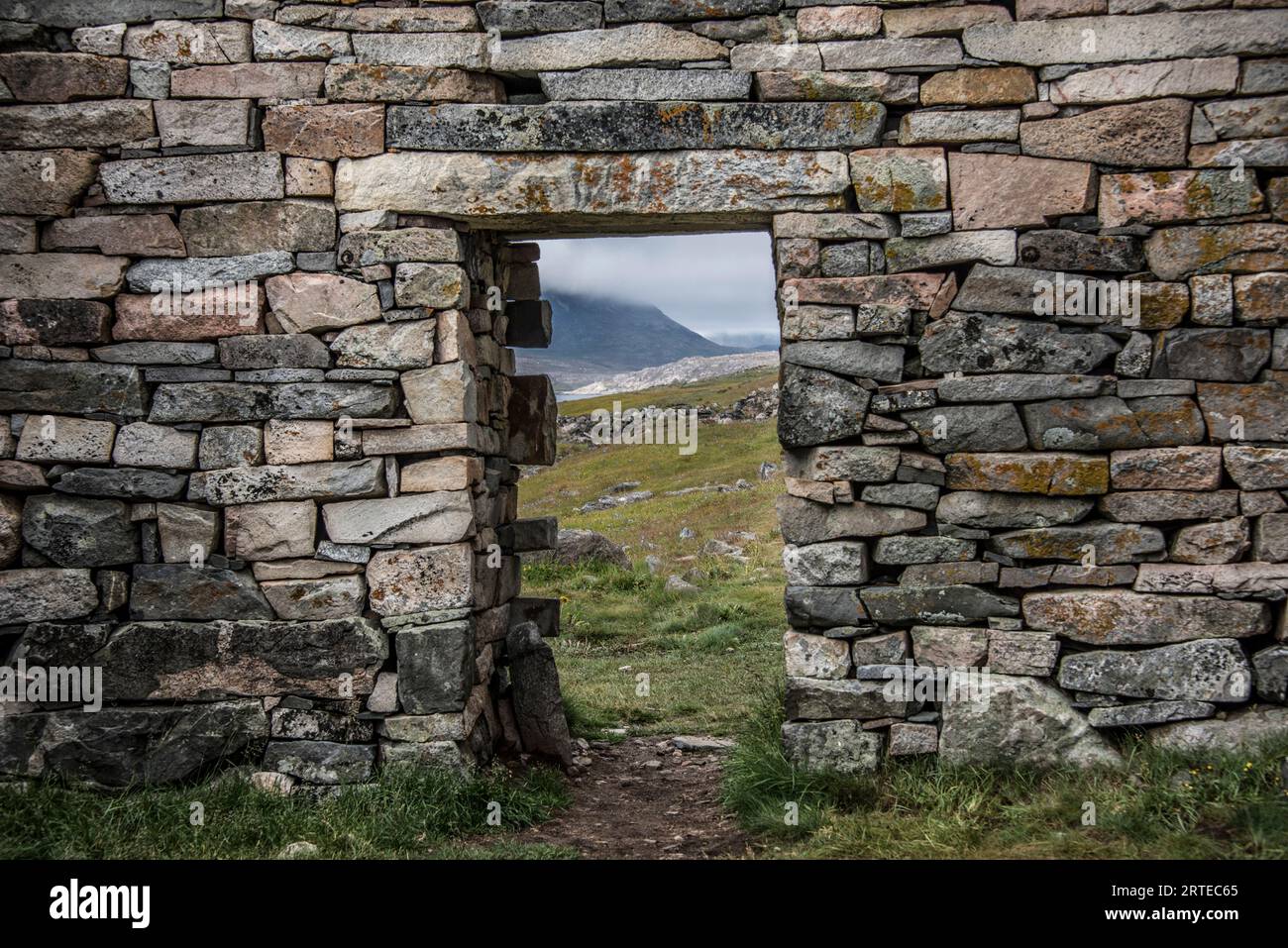 Close-up of a stone wall with an opening looking through to a scenic ...
