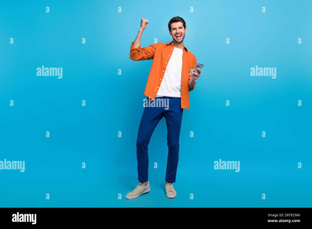 Full size photo of excited delighted guy hold smart phone raise fist ...