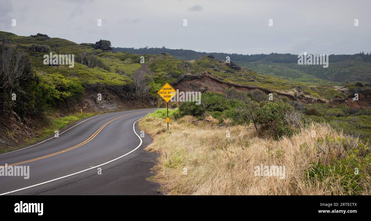 View of a winding road with traffic sign through the green hills on a ...