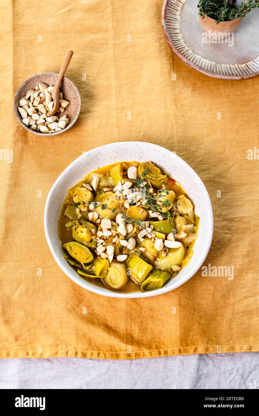 Poached leeks in white wine with garlic, thyme and almonds Stock Photo ...