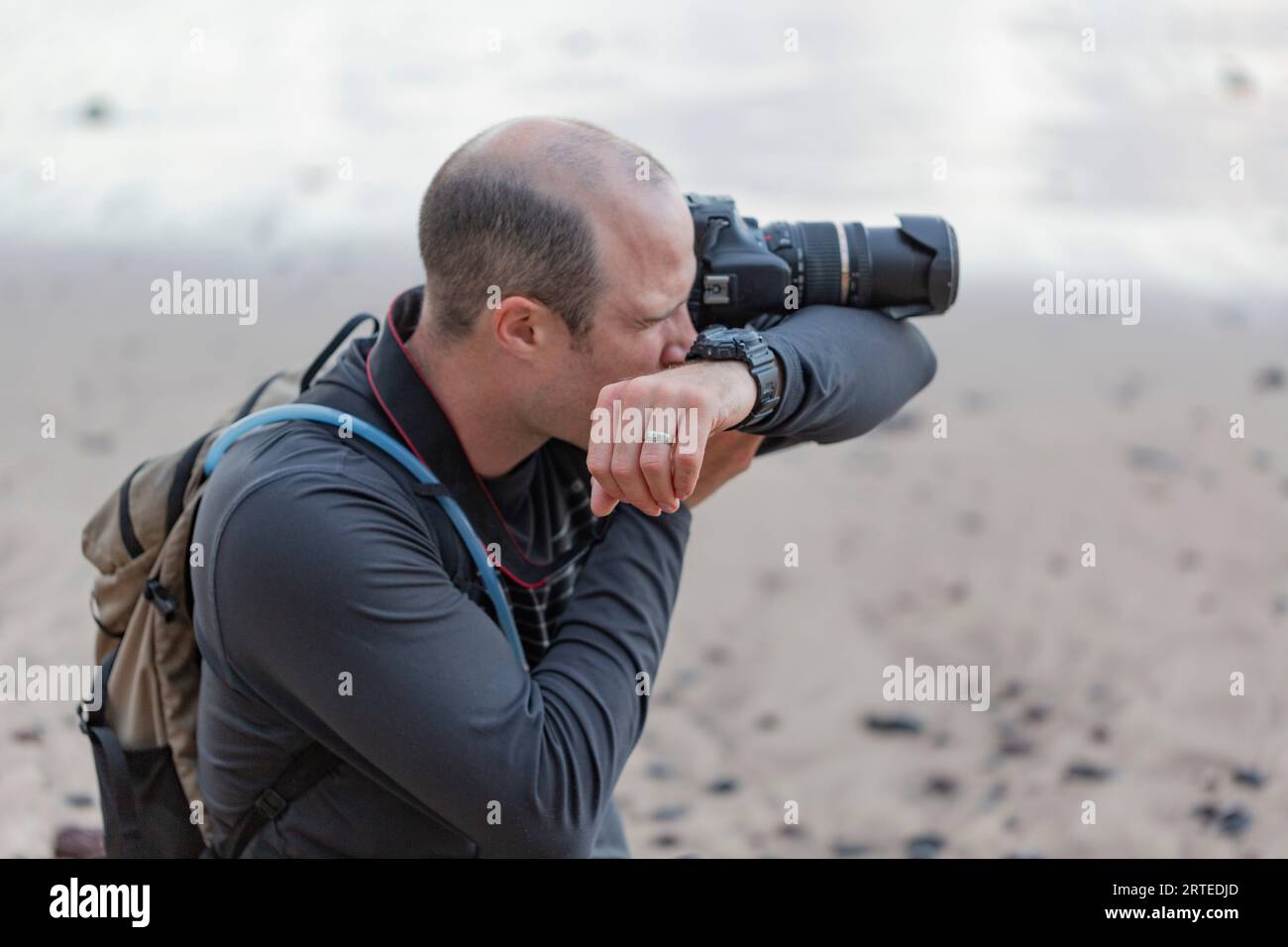 Close-up of a man using his arm to balance camera with telephoto lens ...