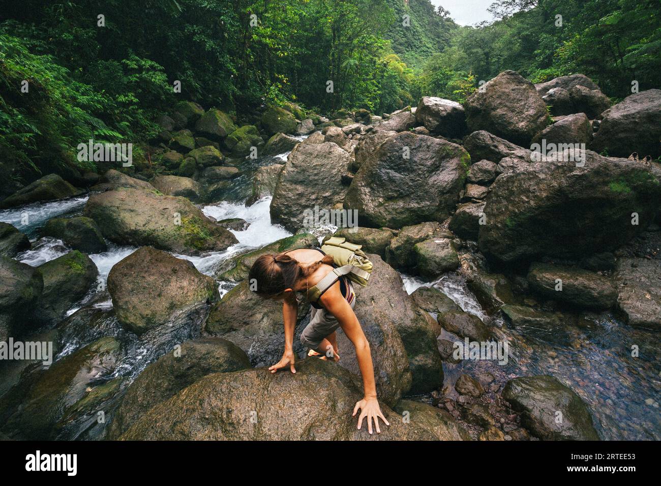 Overhead view of a woman climbing over the slippery, wet rocks along ...