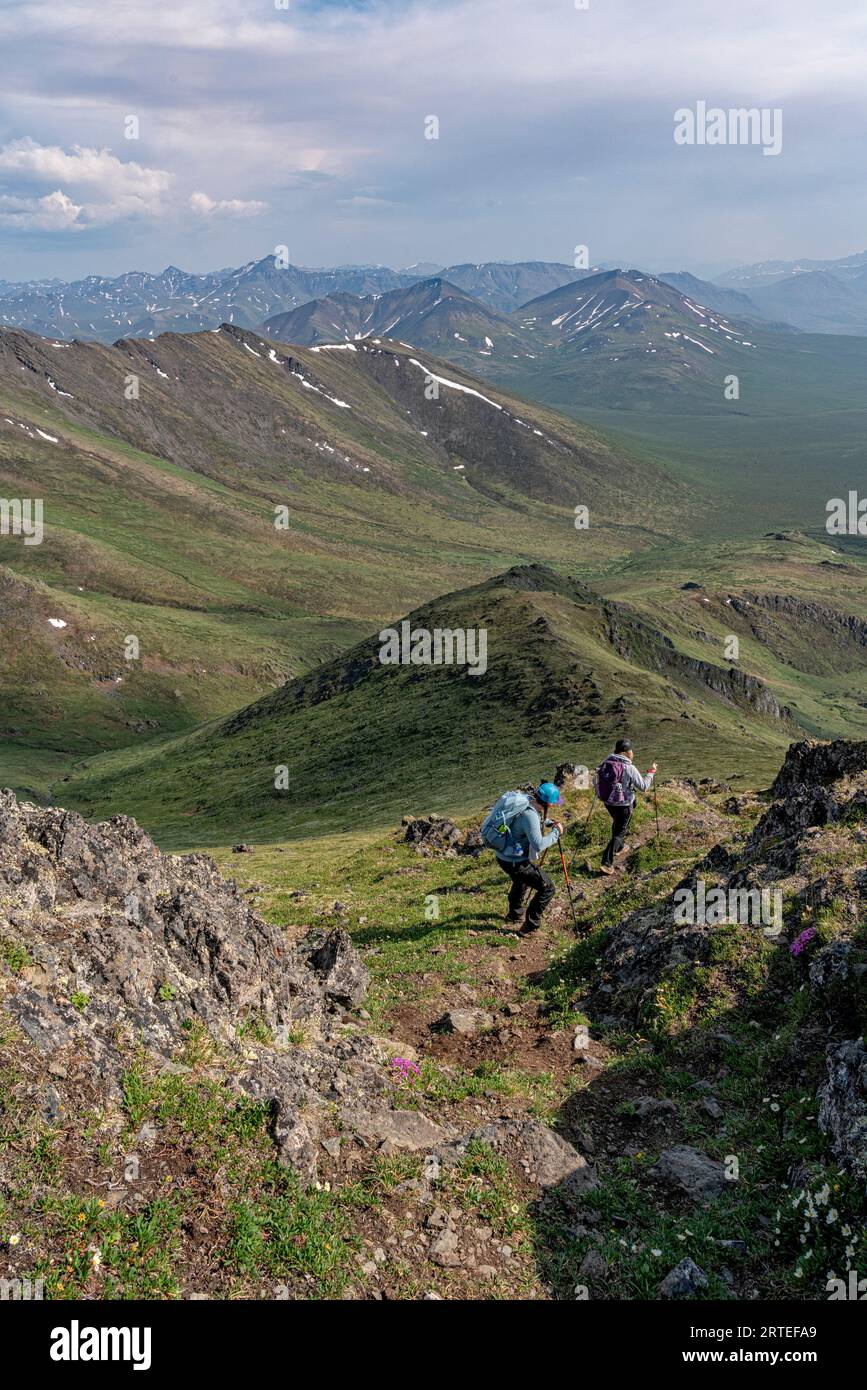 Two women hiking down a mountain side in Northern Yukon with beautiful ...