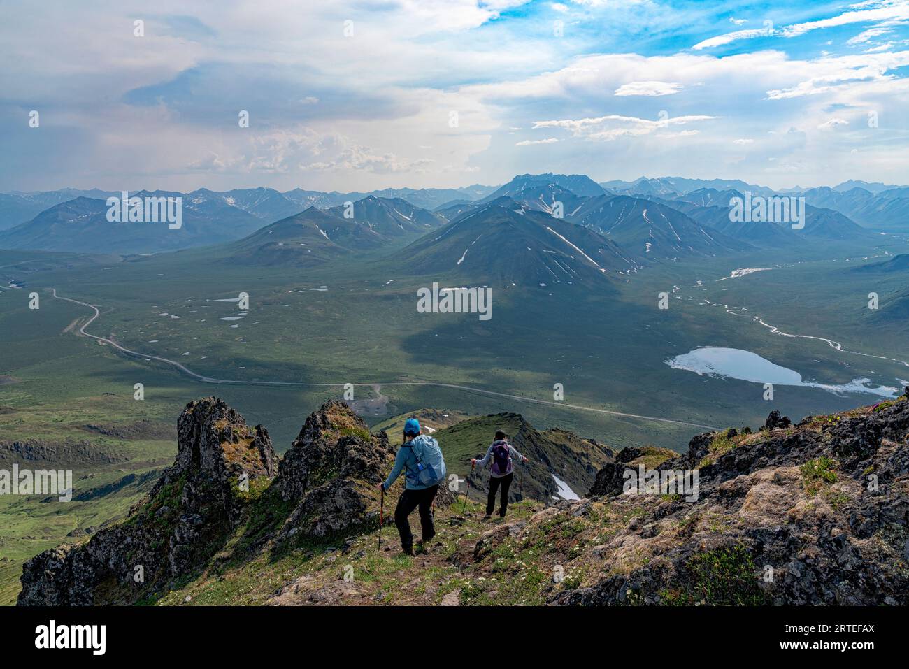 Two women hiking down a mountain side in Northern Yukon with beautiful ...