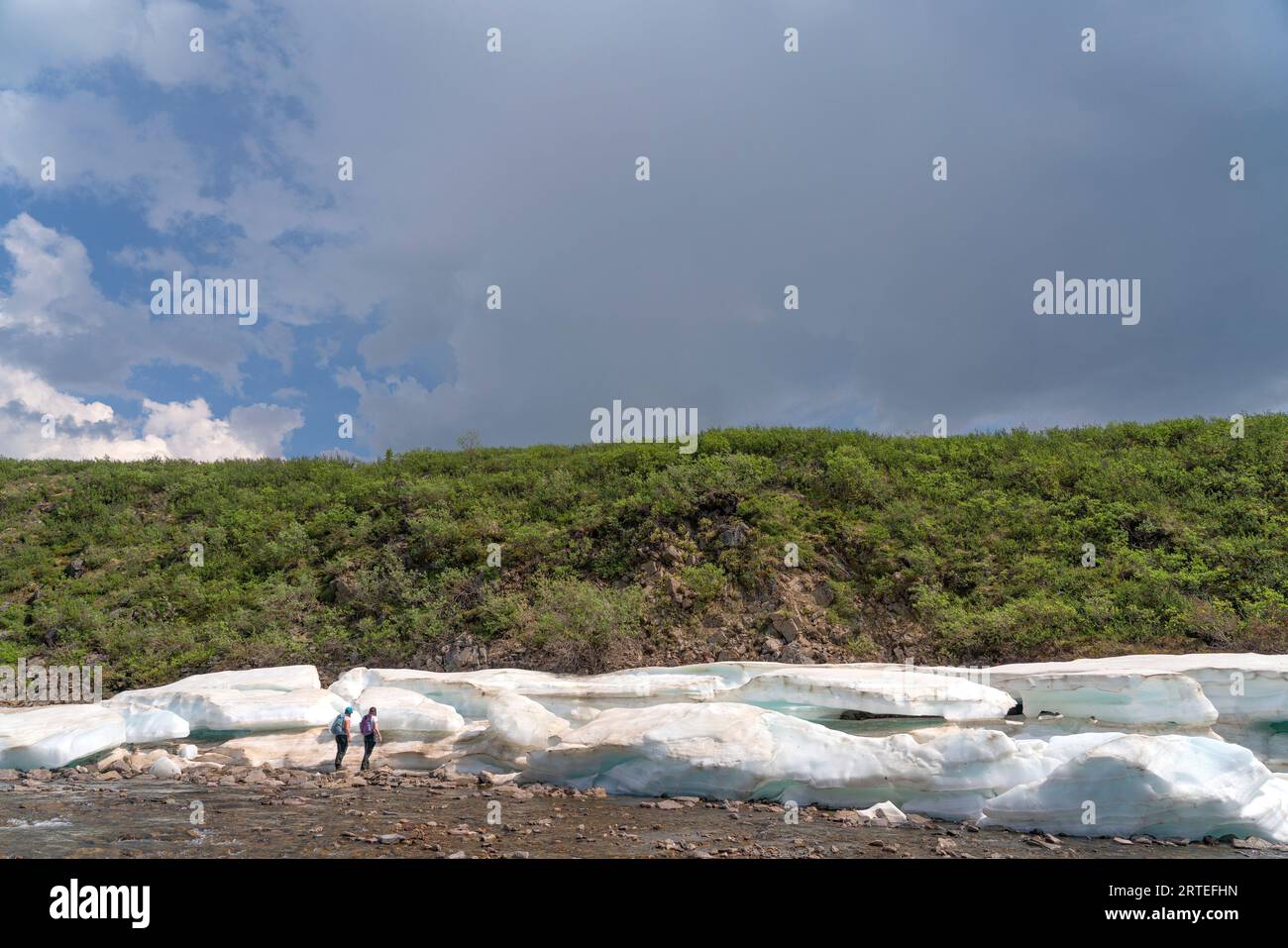 Two women exploring the late season ice known as aufeis (created by ...