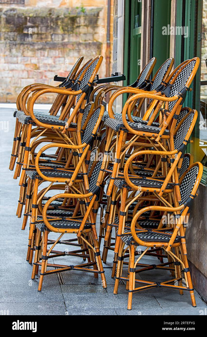 Black and white, bamboo chairs stacked in rows on a sidewalk outside of ...