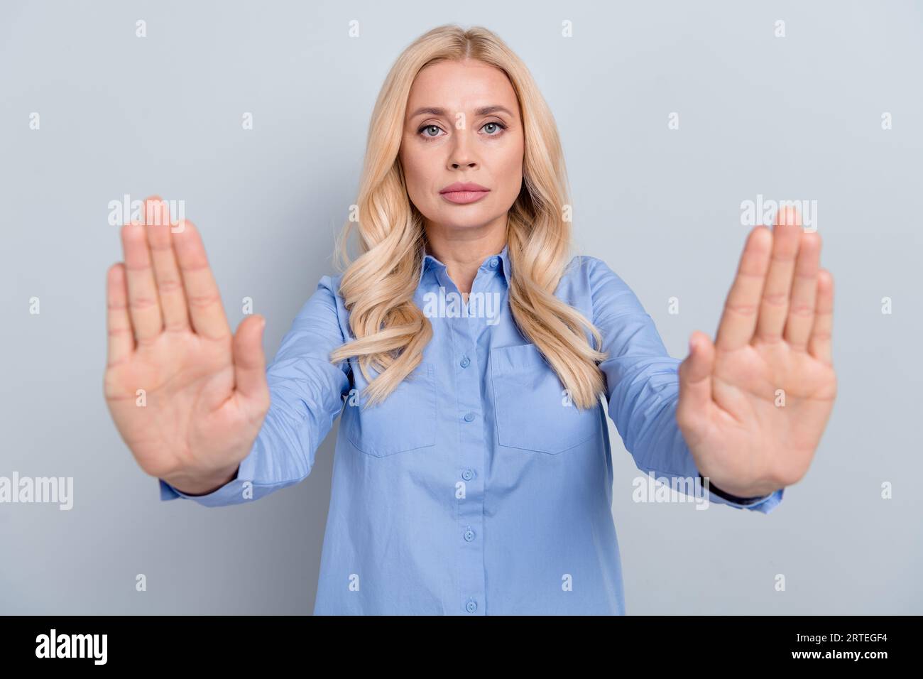 Portrait of serious mature age worker woman raising arms showing ...