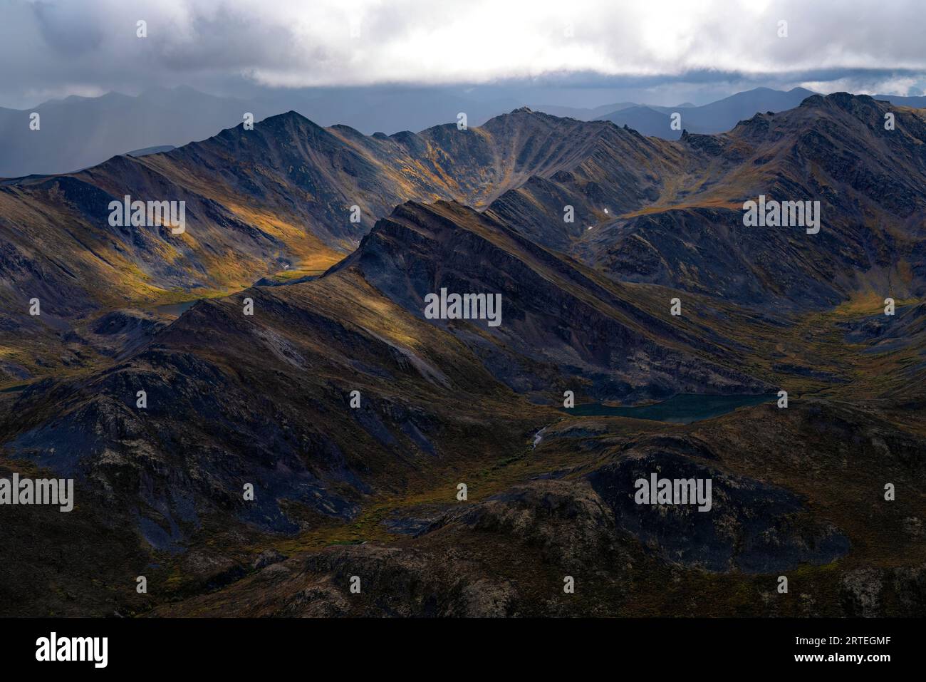 Aerial view of rugged mountain peaks and dark shadows cast onto a ...