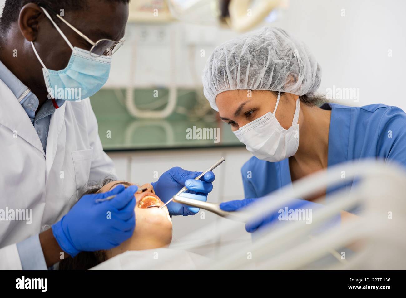 Dentist and assistant doing tooth restoration for female patient Stock ...