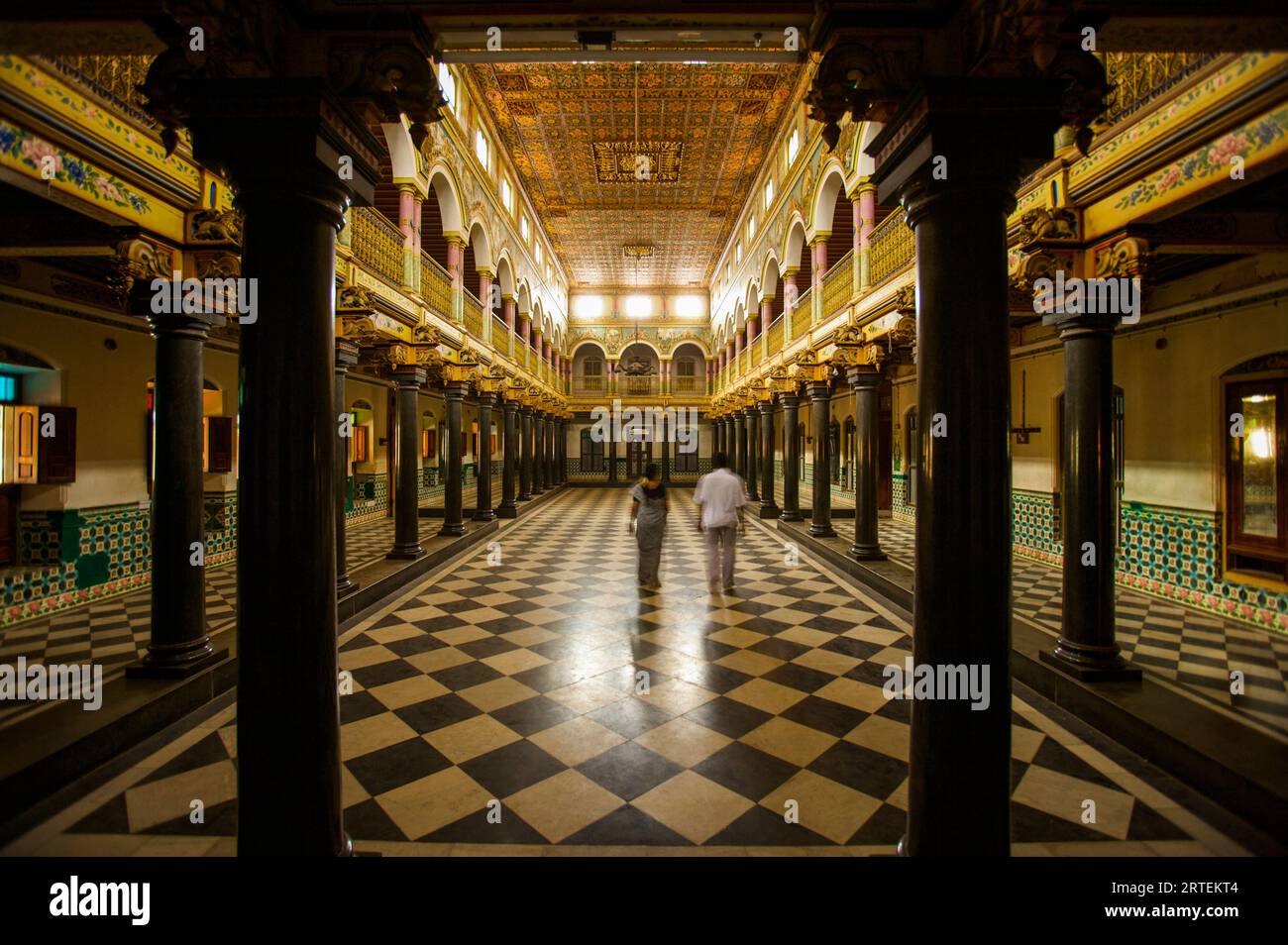 Man and woman walk inside a mansion in Chettinad; Chettinad, Tamil Nadu ...
