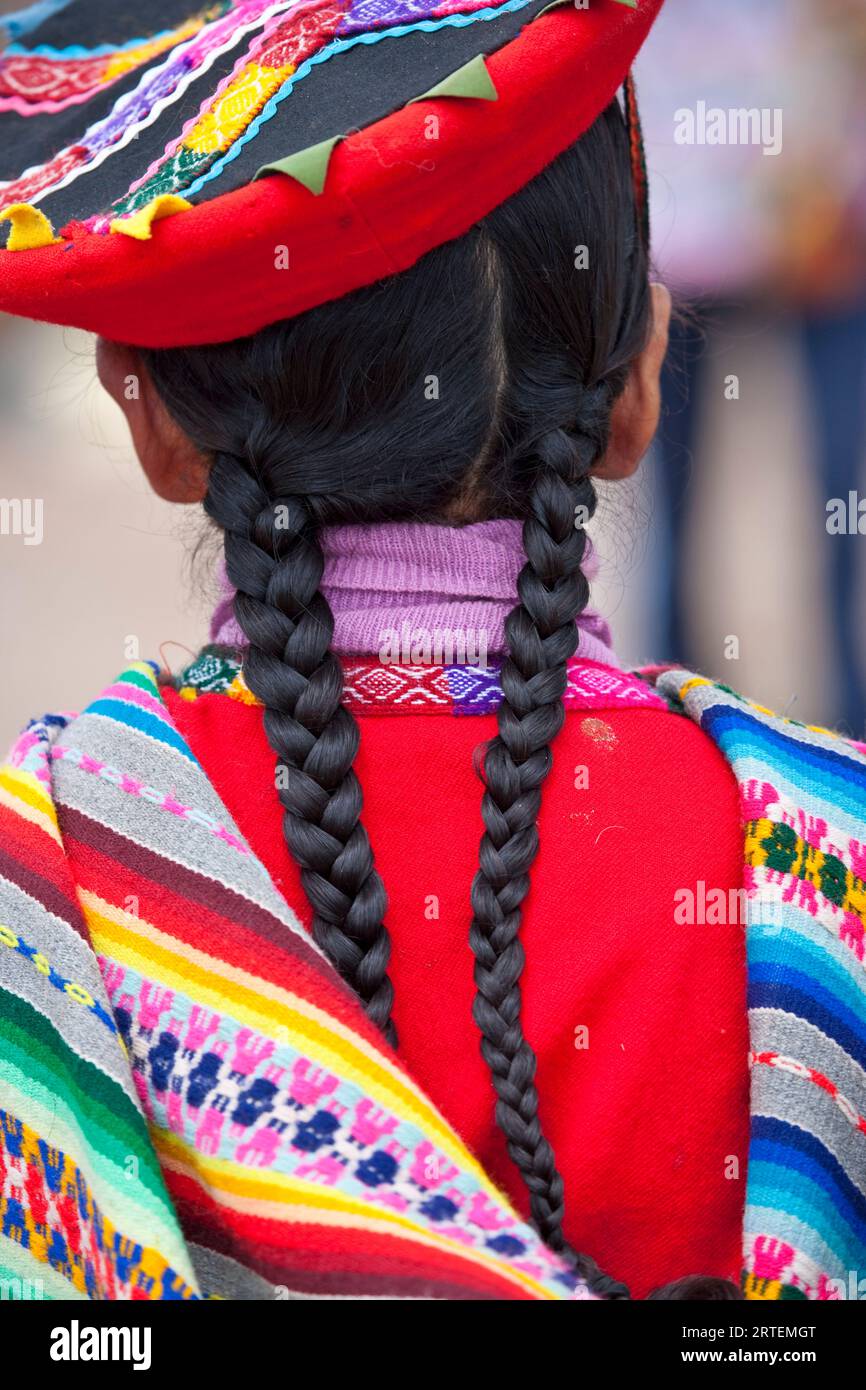 Rear view of a young girl with braids in traditional Peruvian clothing ...