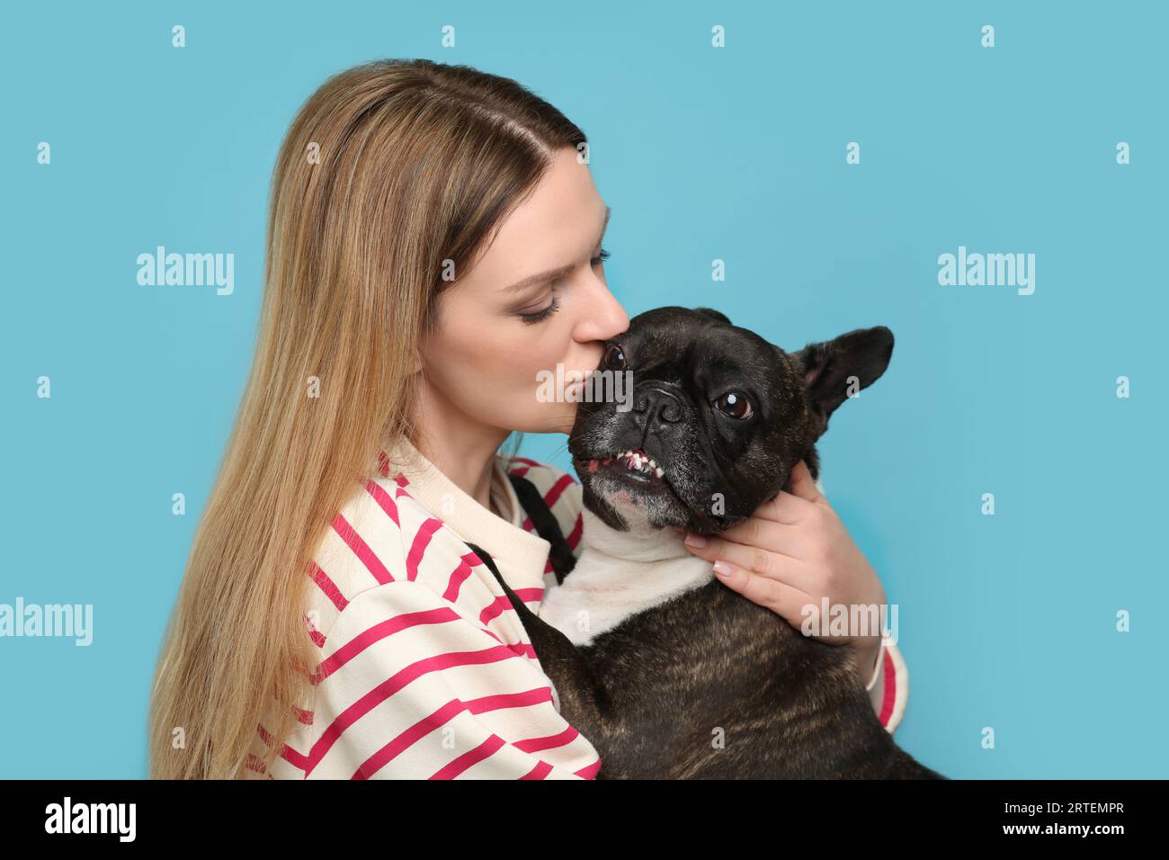 Woman hugging cute French Bulldog on light blue background Stock Photo ...