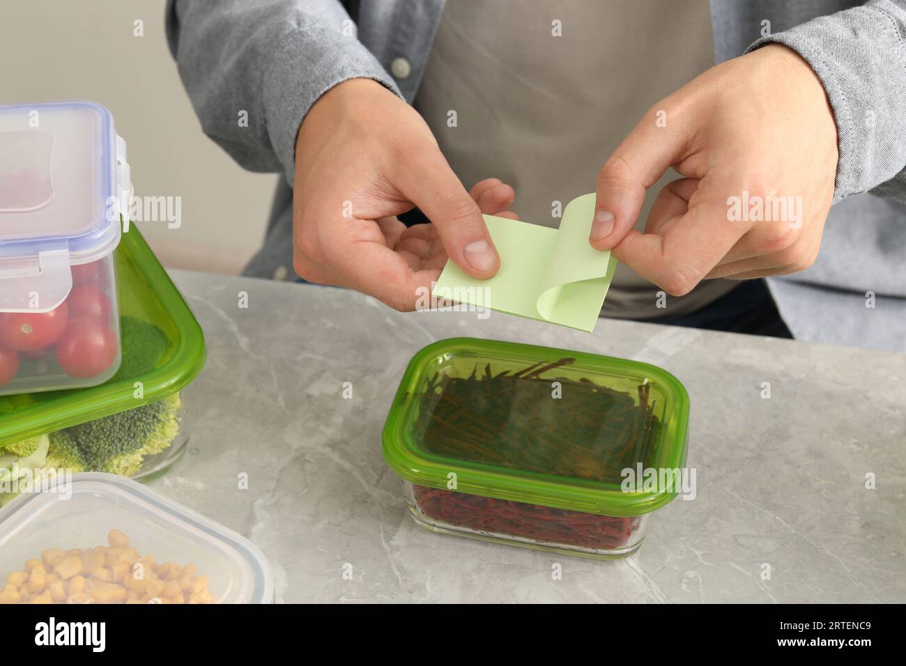Man sticking paper note onto container with cut beets at light grey ...