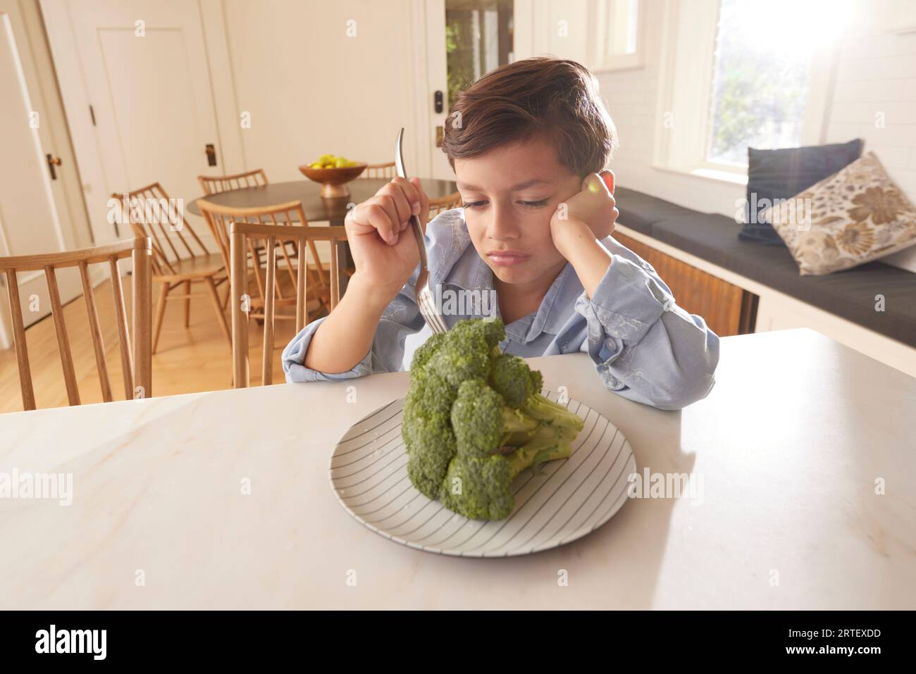 Displeased boy (8-9) looking at broccoli on plate in kitchen Stock ...
