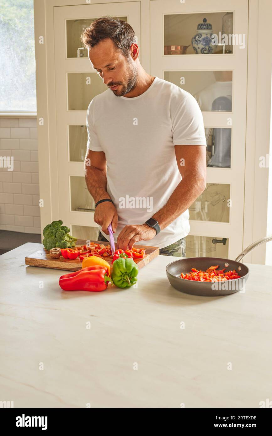 Man cutting vegetables in kitchen Stock Photo - Alamy