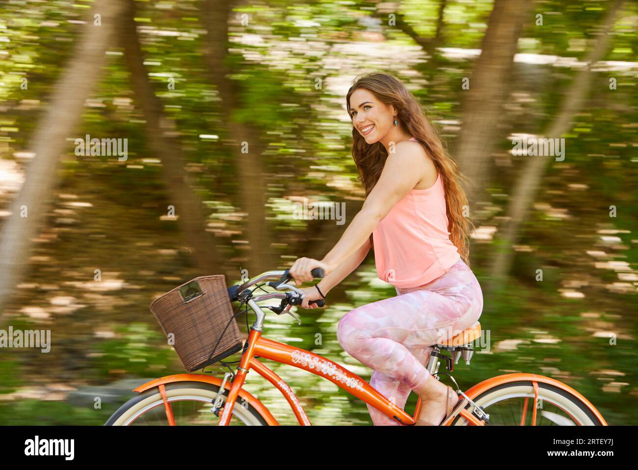 Smiling young woman riding bicycle hi-res stock photography and images ...