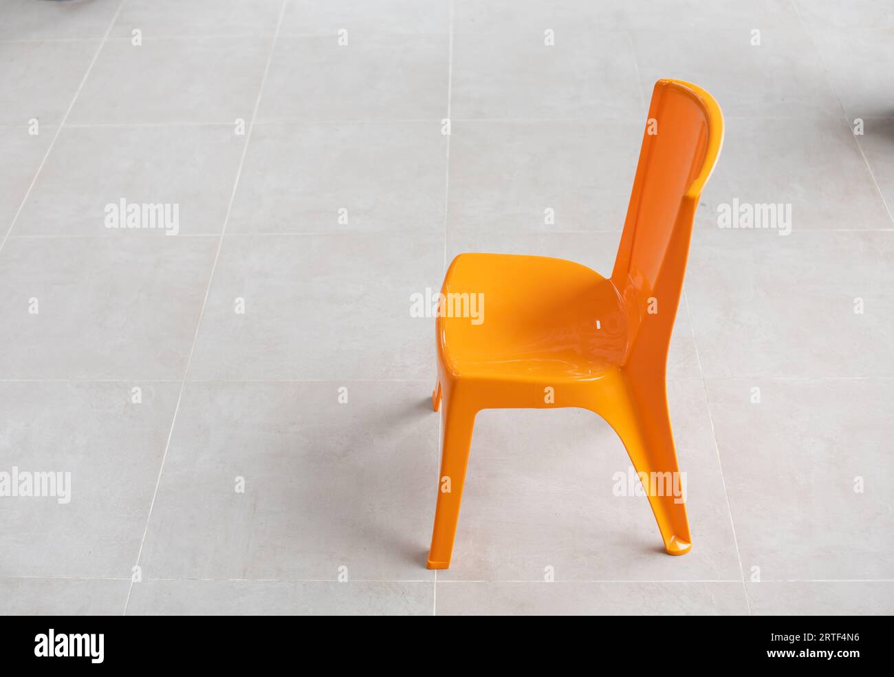 orange plastic chair lays on a gray background Stock Photo - Alamy
