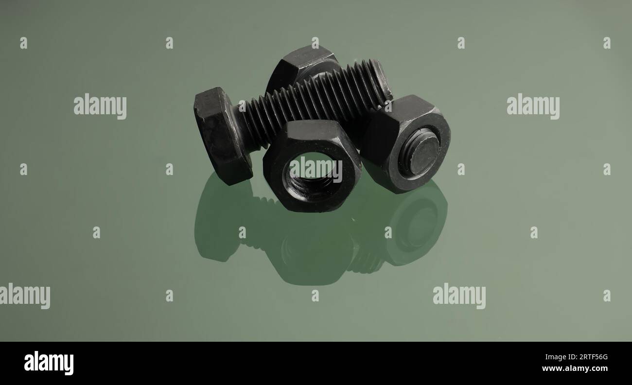 Black anodized bolt and nut placed on a reflective surface. Detailed ...