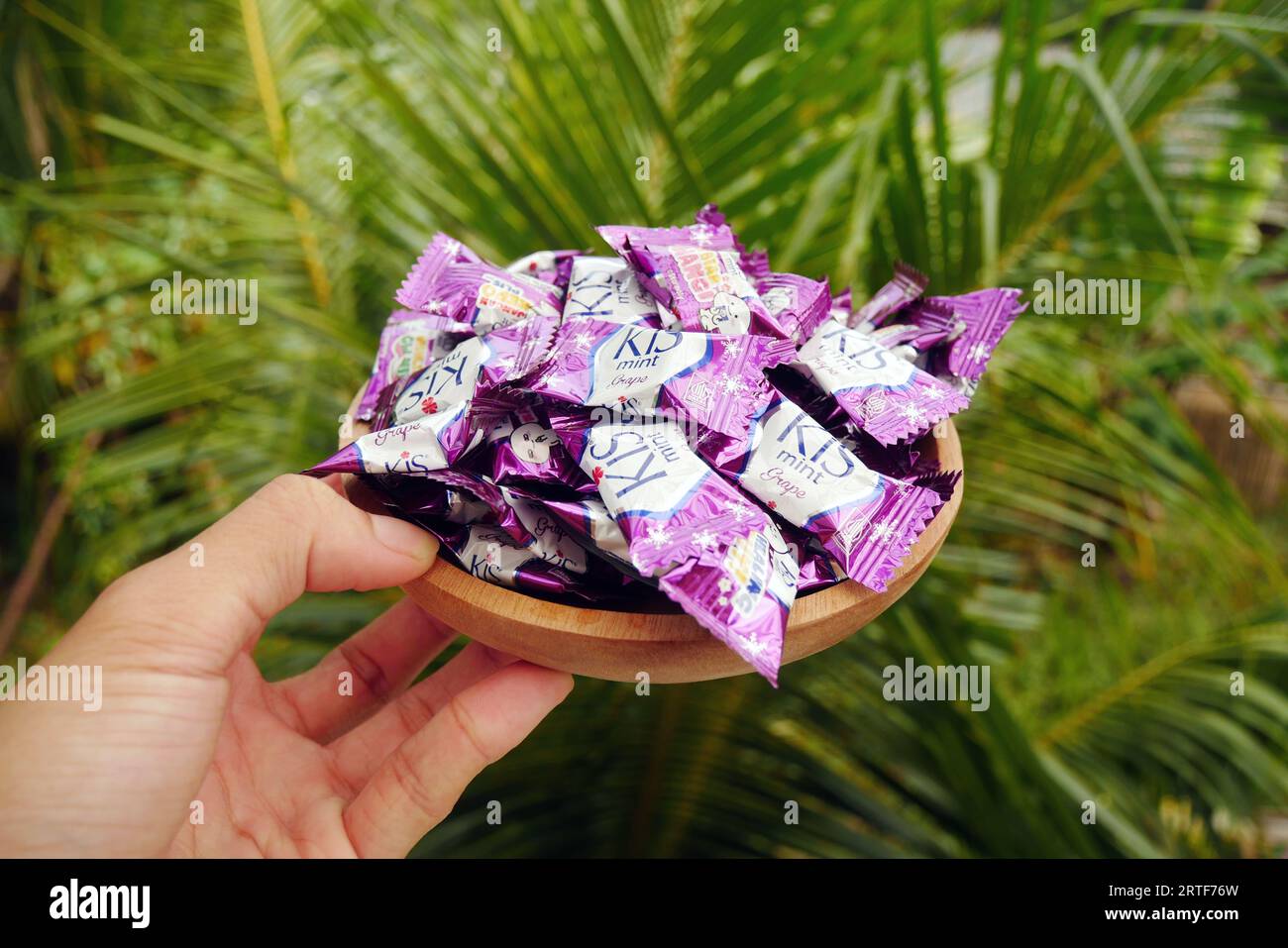 Hand holding wooden bowl with nice of sweet kis candy brand on white ...