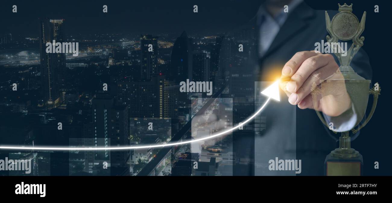 A businessman draws an upward arrow towards a trophy on a city ...