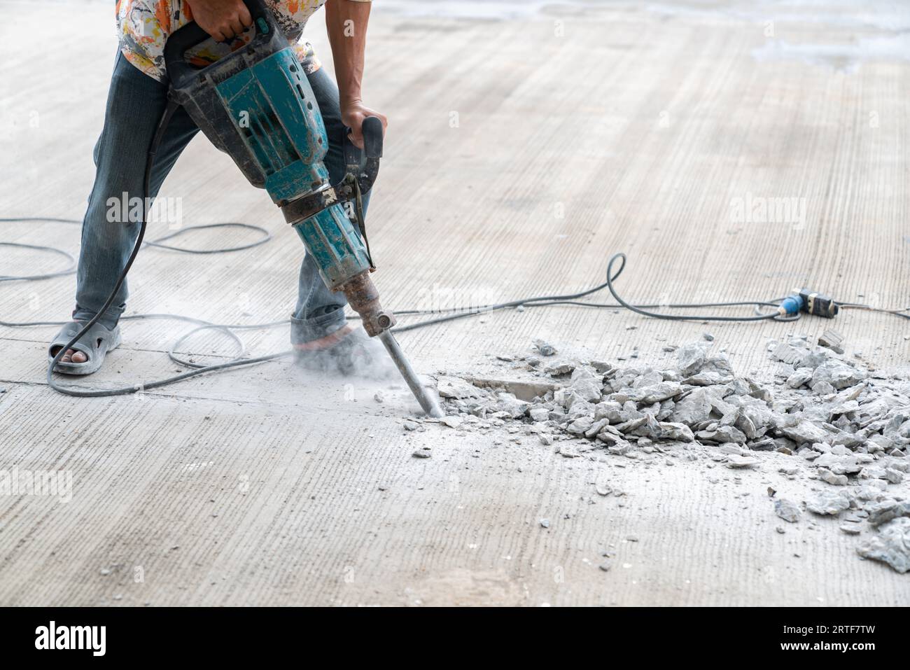 Worker at construction site demolishing concrete with electric jack ...