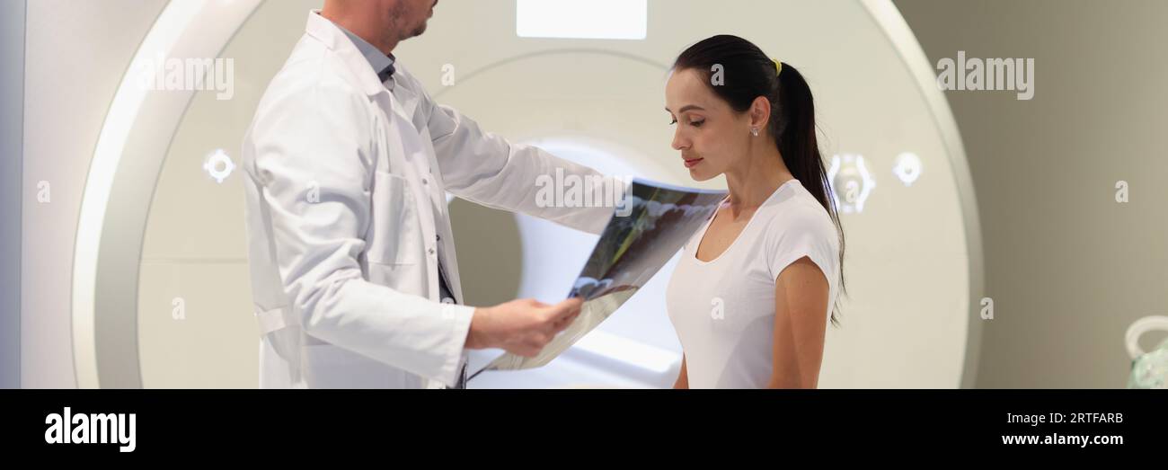 Radiologist looks at MRI results and puts his hand on shoulder of sad ...