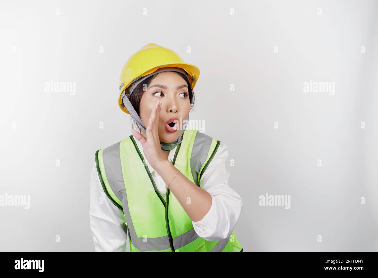 Young beautiful woman labor wearing safety helmet and vest is shouting ...