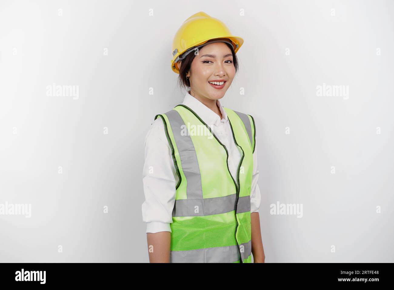A smiling Asian woman labor wearing safety helmet and vest, isolated by ...