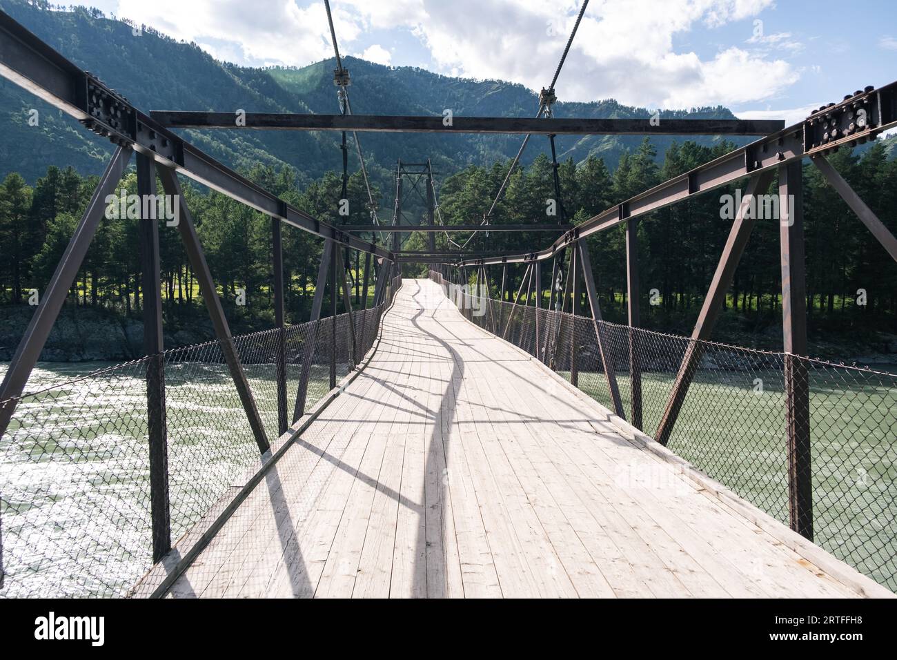 A wooden bridge with metal supports across a raging river Stock Photo ...