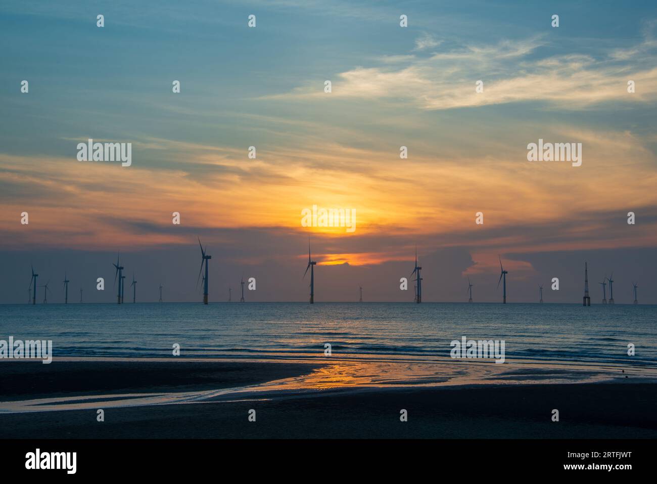Fans of wind turbines spin over the sparkling sea. Dynamic clouds at ...