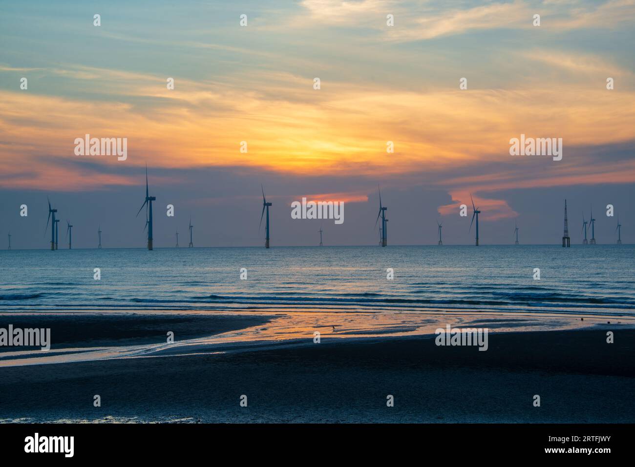 Fans of wind turbines spin over the sparkling sea. Dynamic clouds at ...