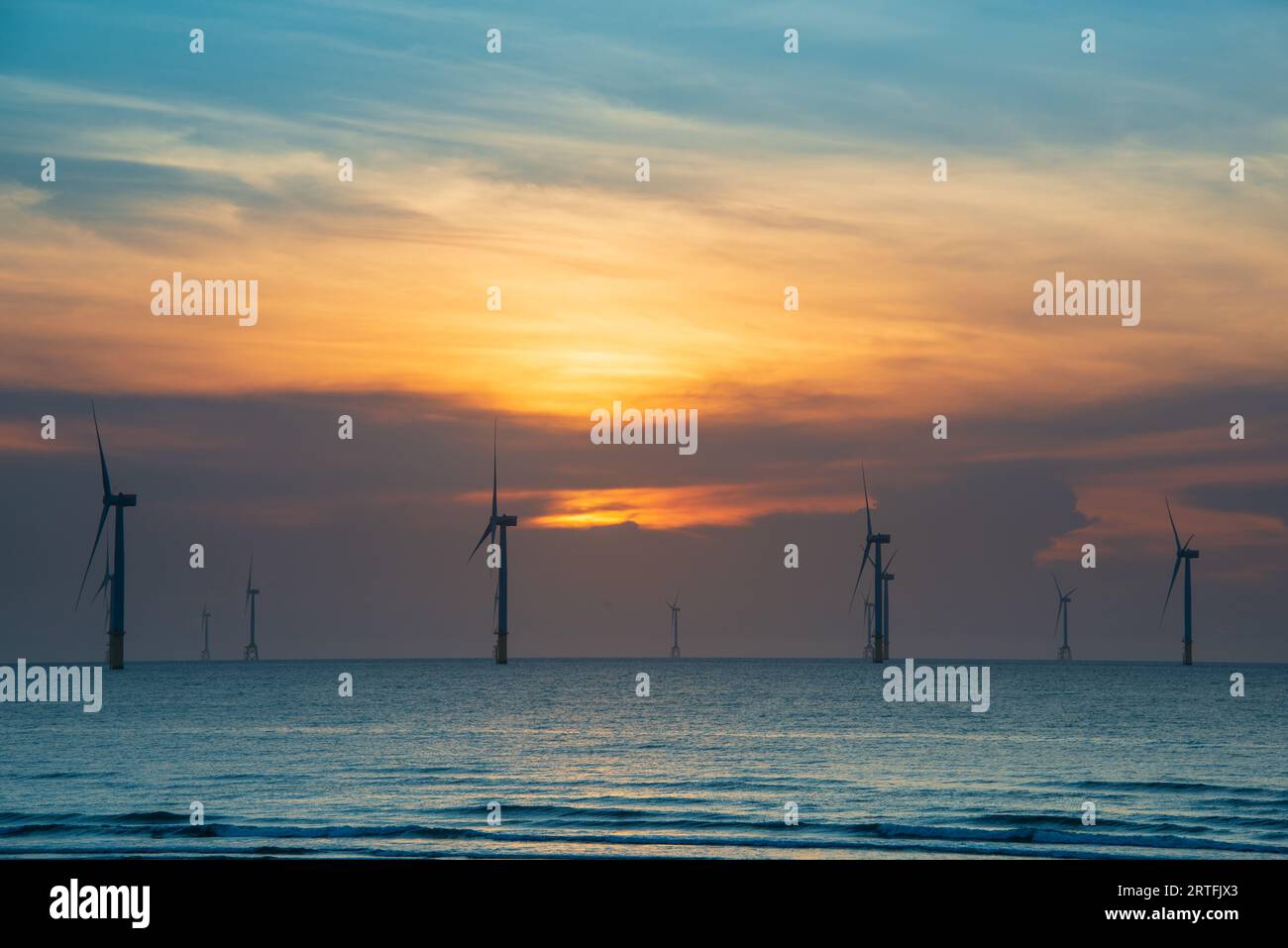 Fans of wind turbines spin over the sparkling sea. Dynamic clouds at ...