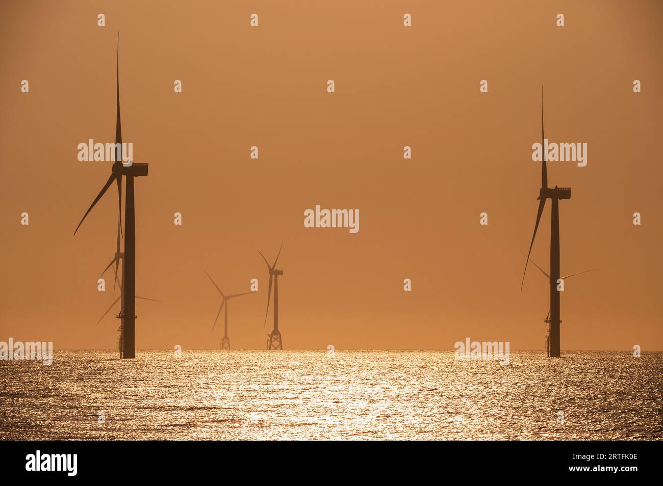 Fans of wind turbines spin over the sparkling sea. Dynamic clouds at ...