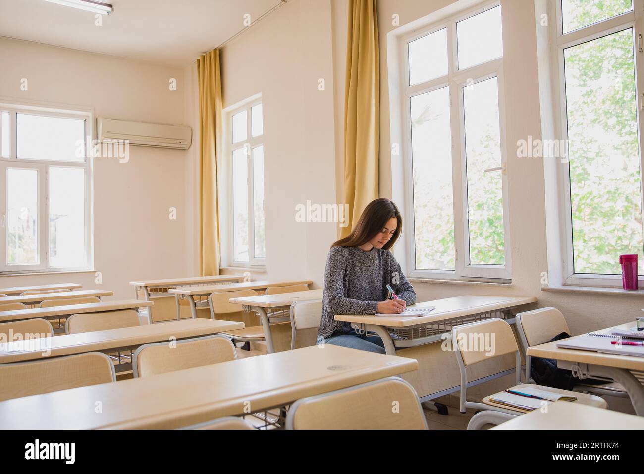 girl alone in classroom, making notes Stock Photo - Alamy