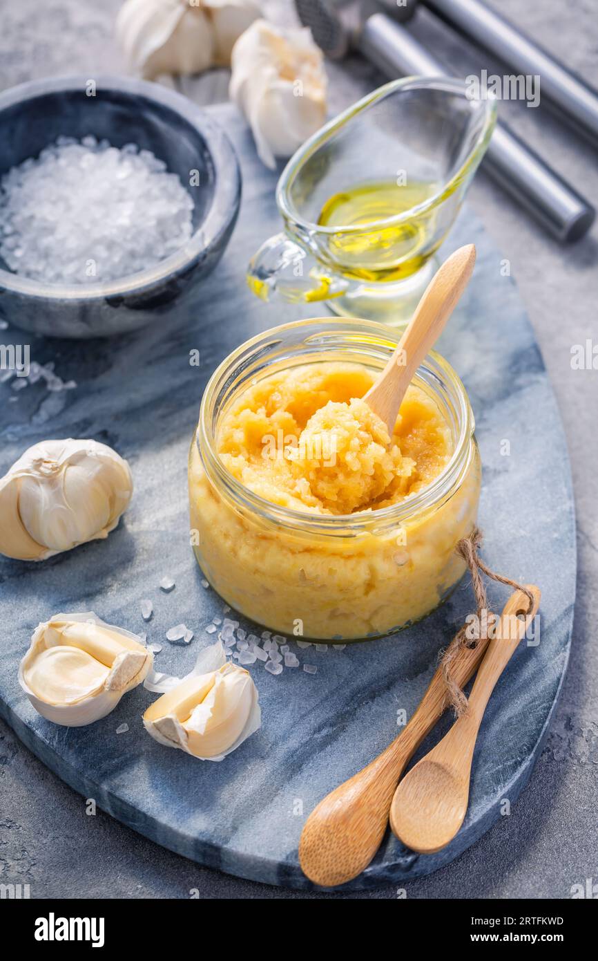 Homemade garlic paste in a jar with peeled garlic, salt, crusher and ...