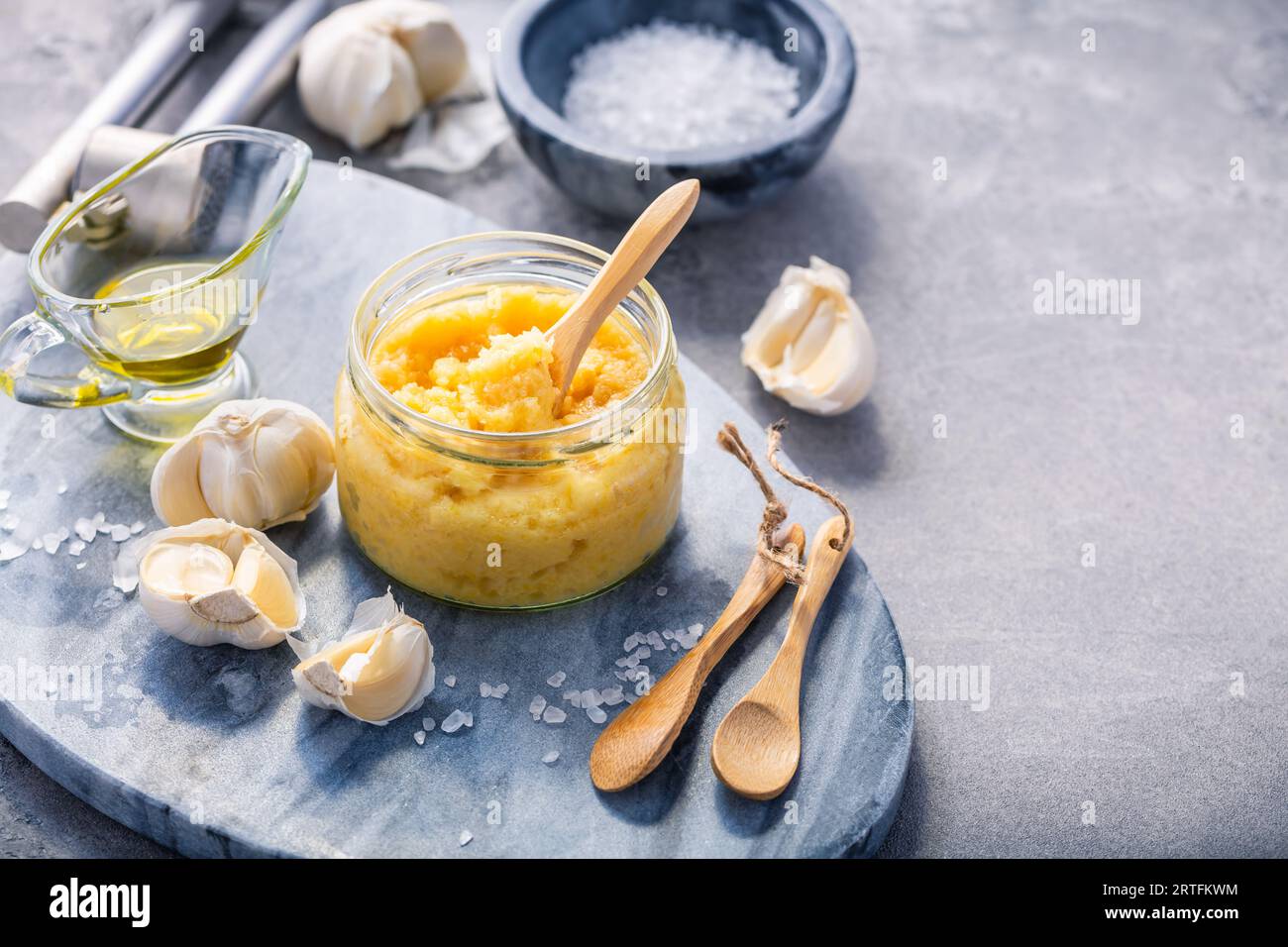 Homemade garlic paste in a jar with peeled garlic, salt, crusher and ...