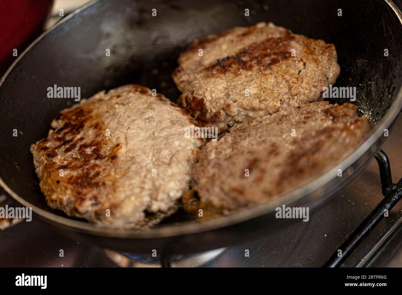 Capturing the moment of a juicy hamburger patty sizzling on a pan atop ...