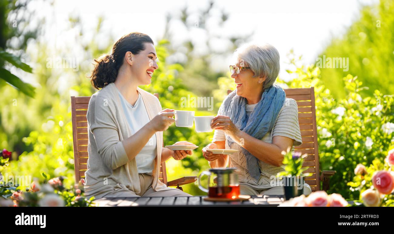Happy young woman and her mother drinking tea in summer morning. Family ...