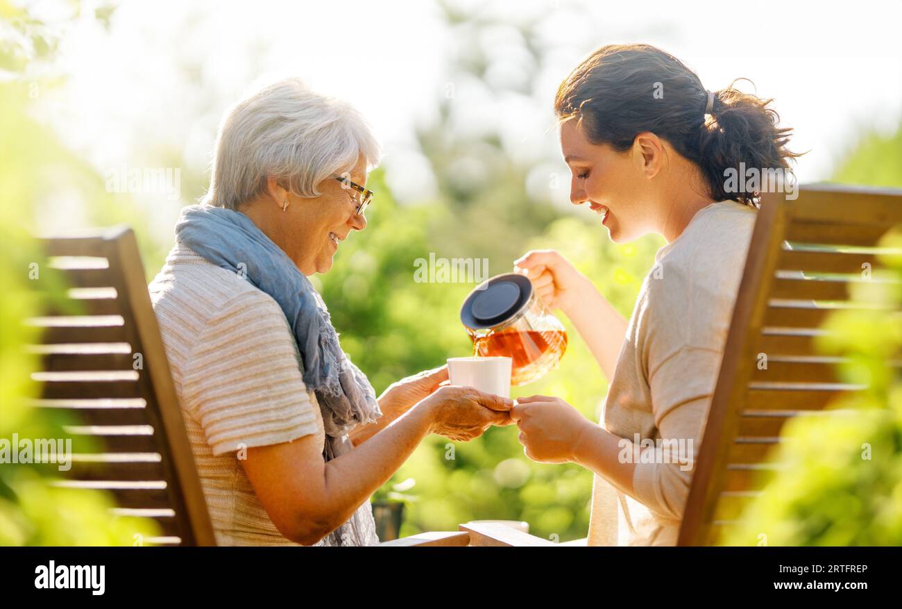 Happy young woman and her mother drinking tea in summer morning. Family ...