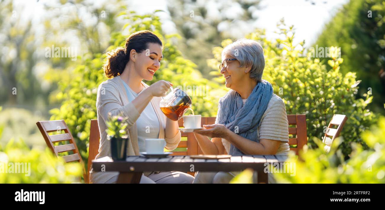 Happy young woman and her mother drinking tea in summer morning. Family ...