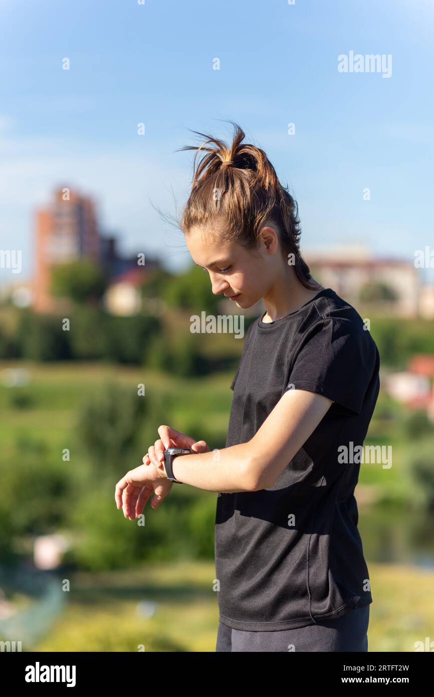 Teenage girl in black clothes checking her fitness watch after a ...