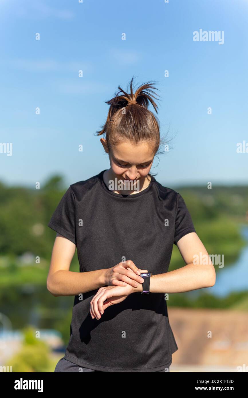 Teenage girl in black clothes checking her fitness watch after a ...