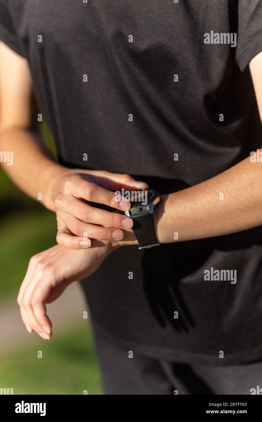 Teenage girl in black clothes checking her fitness watch after a ...