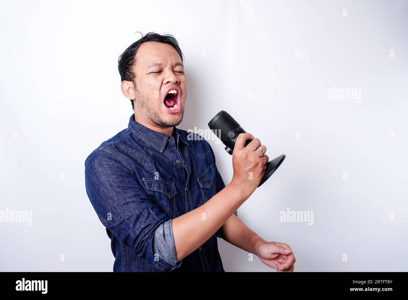 Portrait of carefree Asian man, having fun karaoke, singing in ...