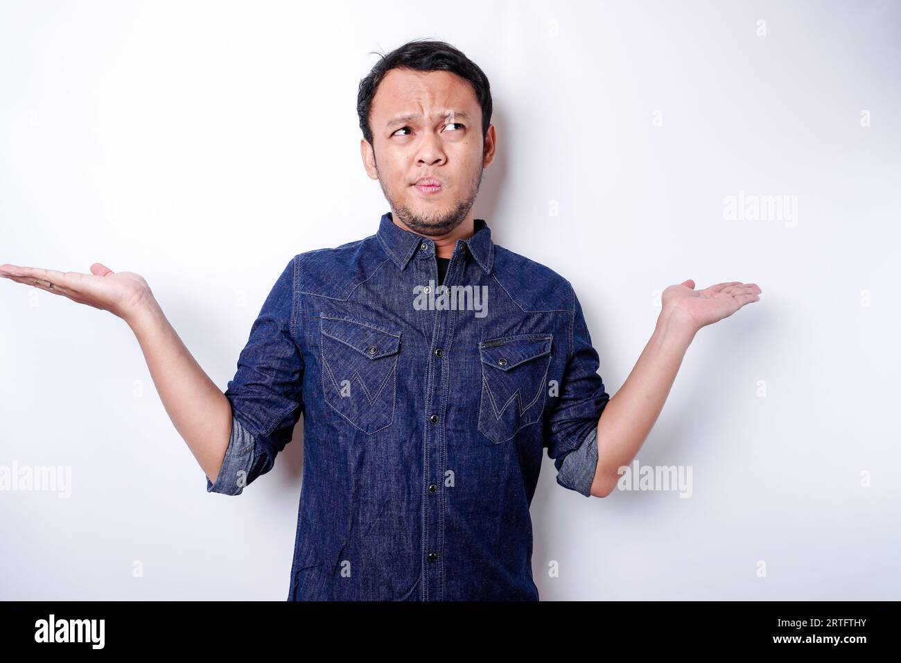 A portrait of an Asian man wearing a blue shirt looks so confused ...