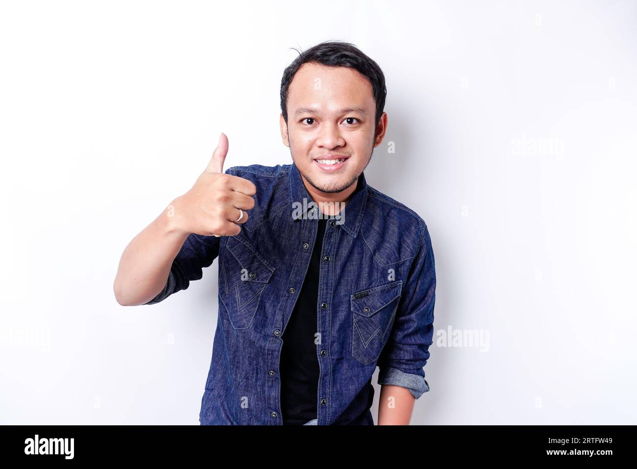Excited Asian man wearing blue shirt gives thumbs up hand gesture of ...